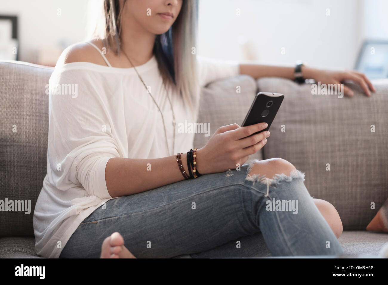 Young woman using mobile phone at home Stock Photo - Alamy