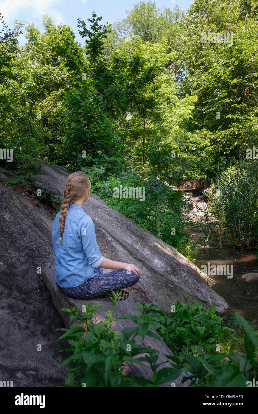 Woman sitting on stone in forest Stock Photo - Alamy
