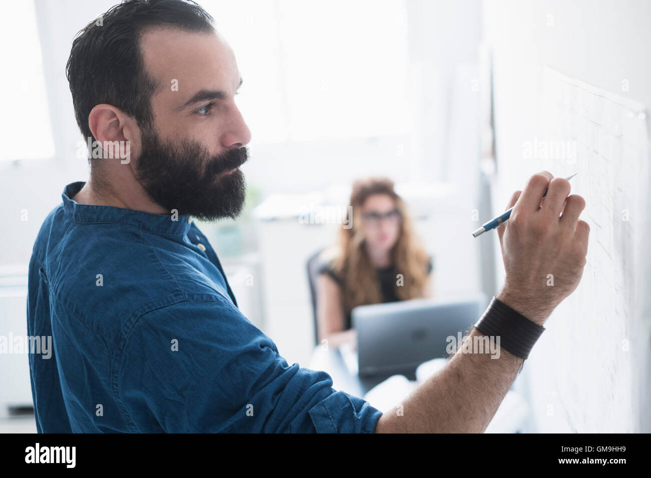 Mid-adult man writing on whiteboard Stock Photo - Alamy