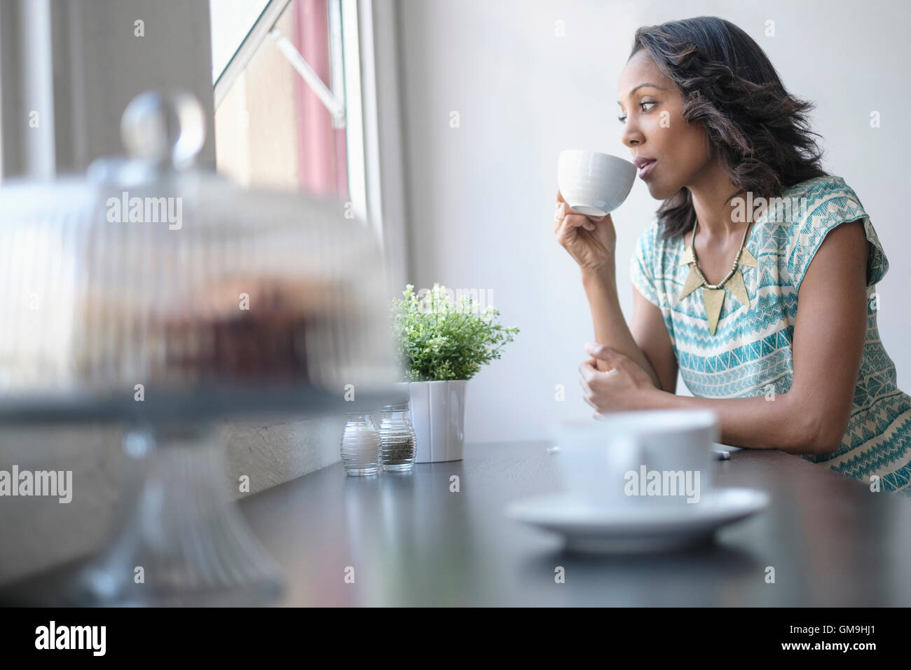 Woman drinking coffee by window Stock Photo - Alamy