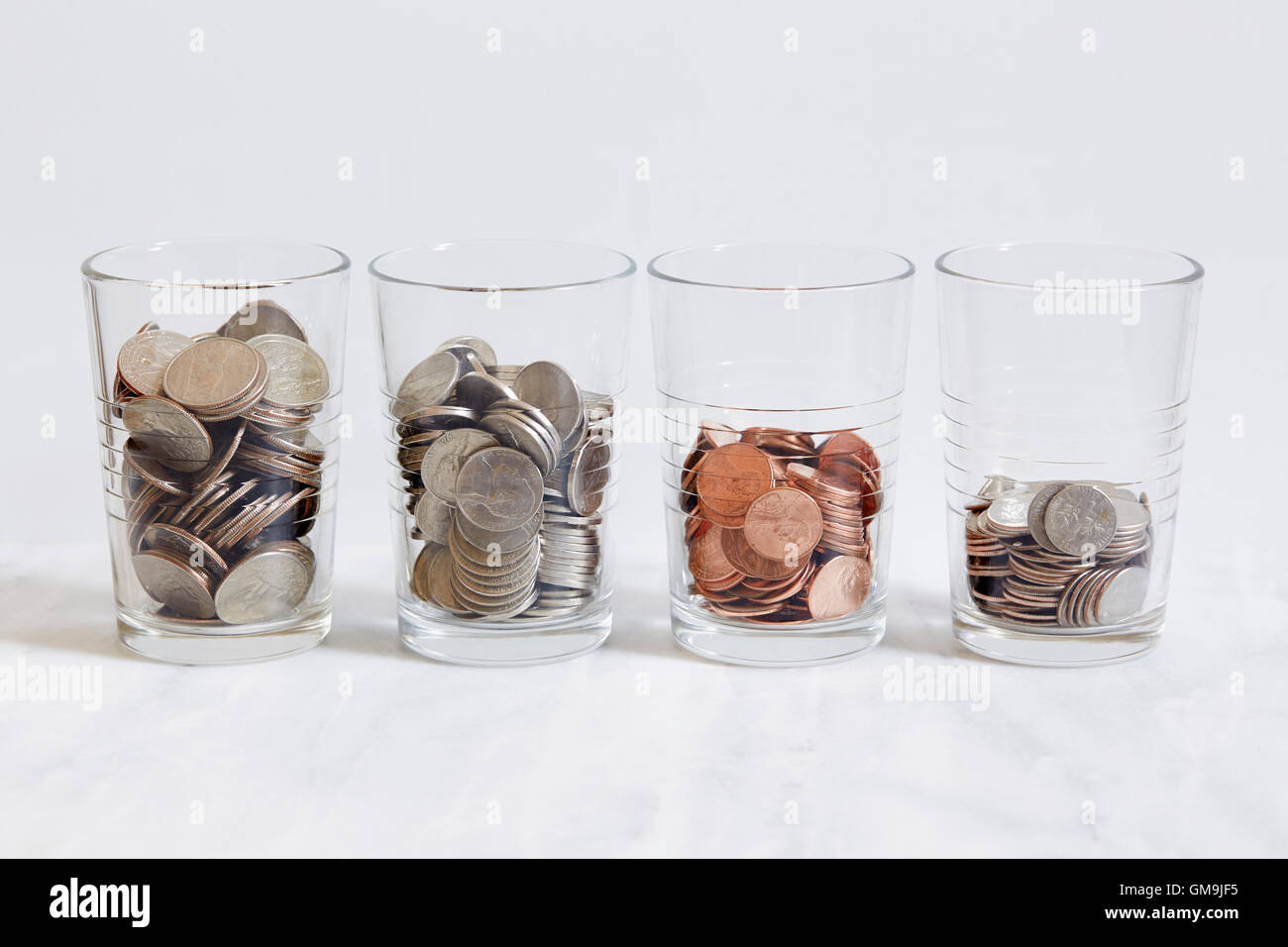Row of glasses with coins Stock Photo - Alamy