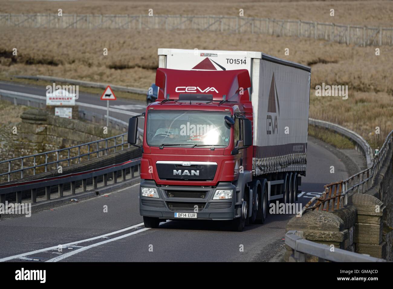 A Ceva Logistics MAN curtainsider truck takes a bend over a bridge on ...