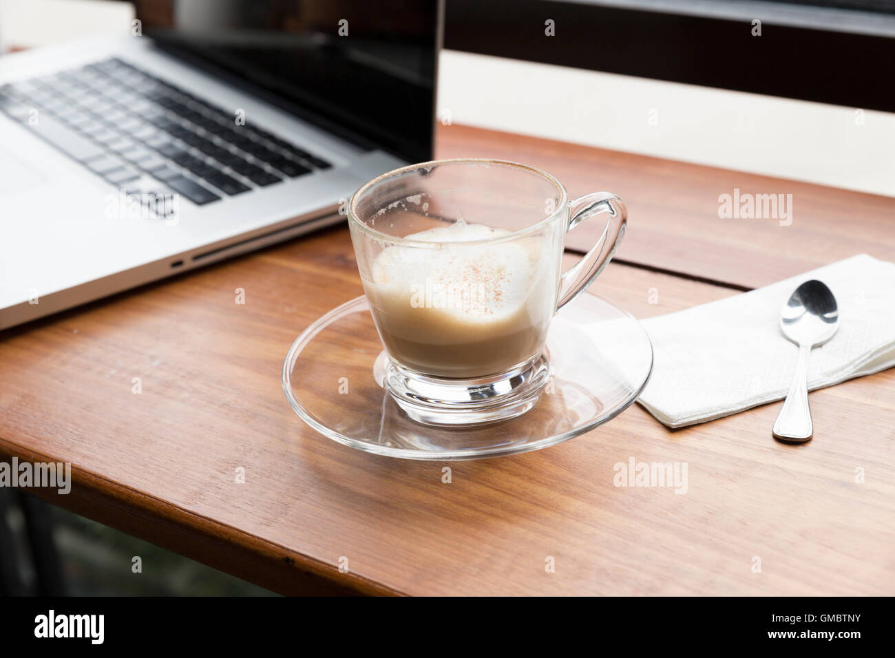 hot cappuccino coffee cup with spoon and laptop computer notebook on ...