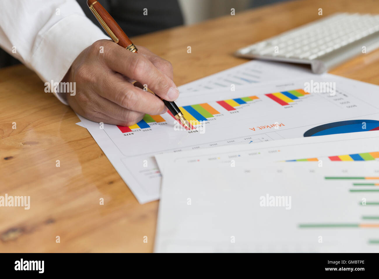 businessman hand holding pen with graph and chart analysis paperwork ...