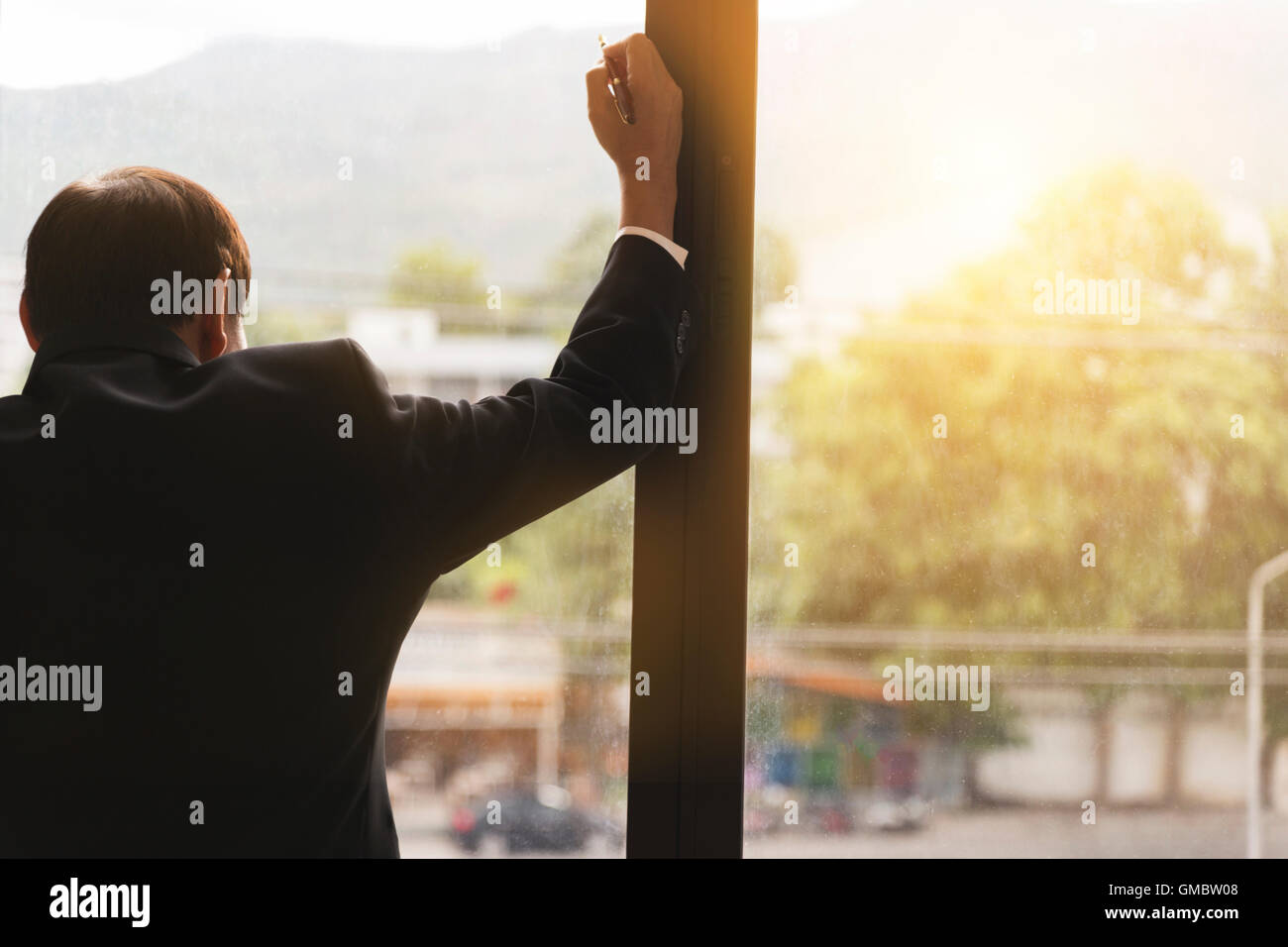 back of businessman in suit looking out through office window Stock ...