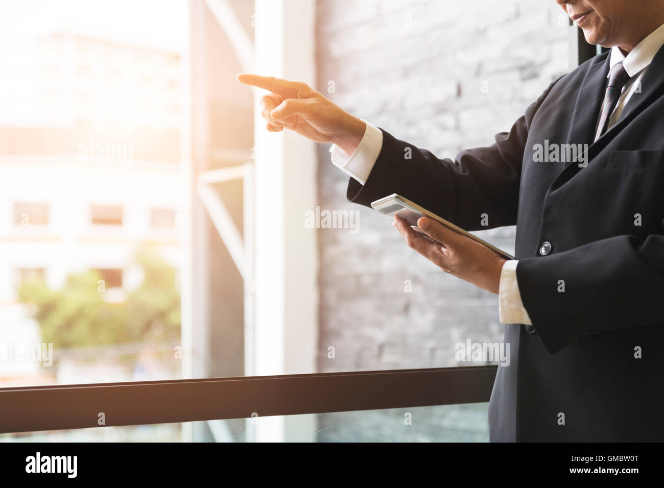businessman holding tablet and pointing his finger out of window Stock ...