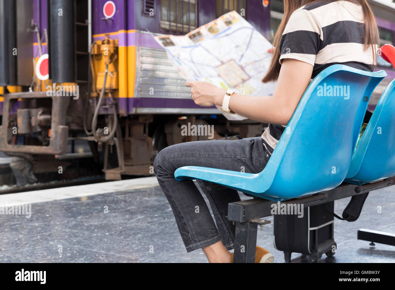 woman with map sitting on chair beside railway in train station Stock ...