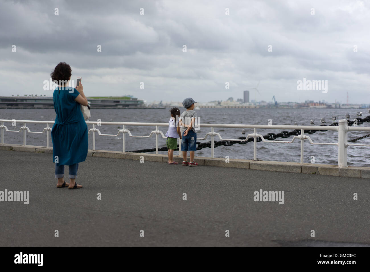 Two children looking into the sea from a shoreline with their mother ...