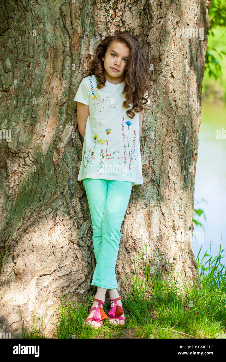 Little Girl on tree trunk on the background of summer park Stock Photo ...