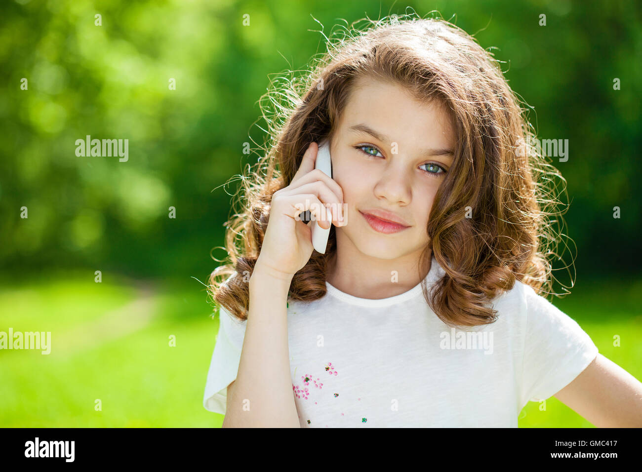 Beautiful little girl calling by mobile phone on the background of ...