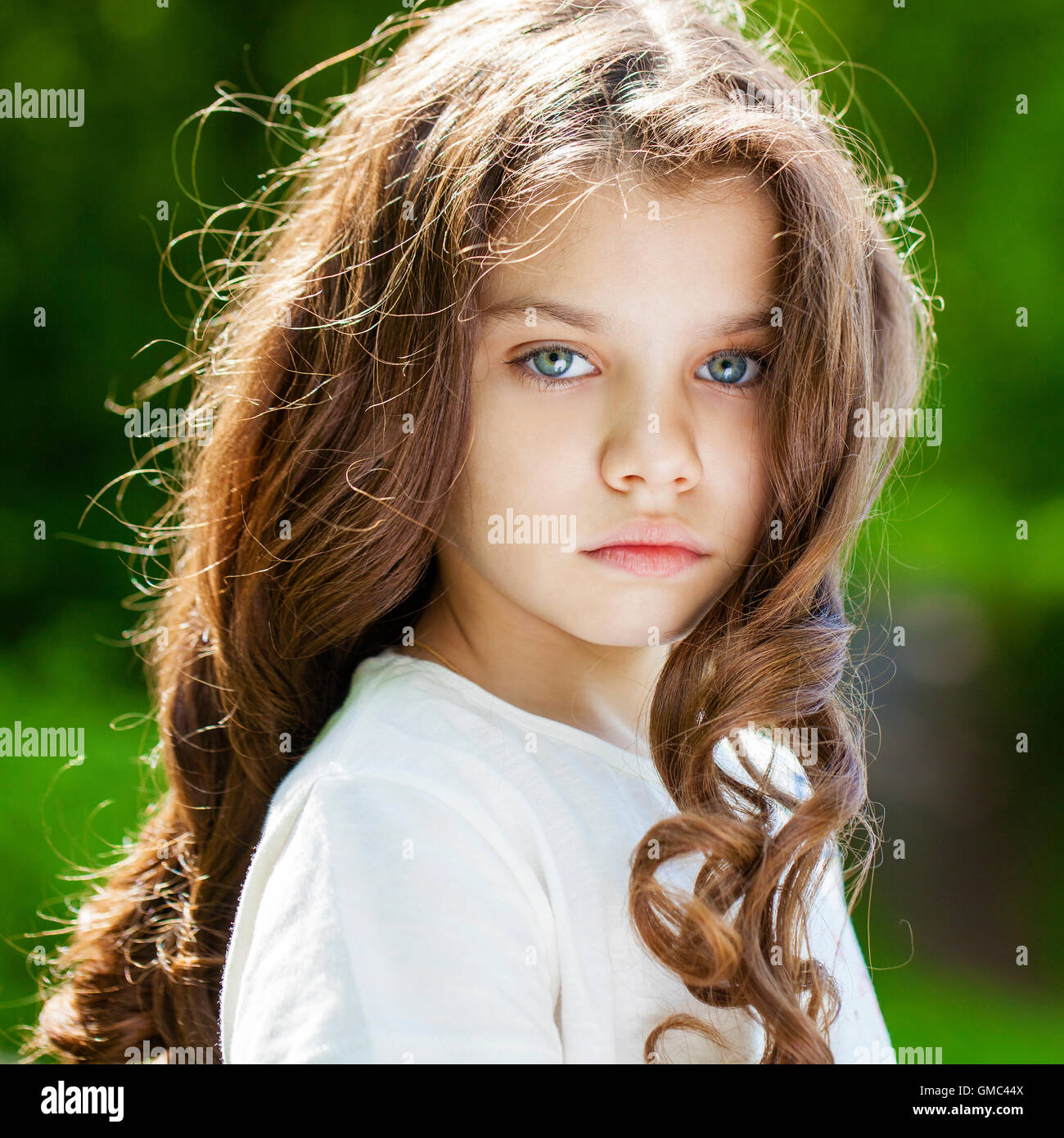 Portrait of a beautiful young little girl on the background of summer ...