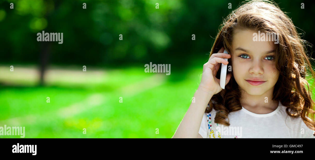 Beautiful little girl calling by mobile phone on the background of ...