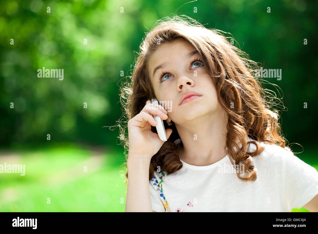 Beautiful little girl calling by mobile phone on the background of ...