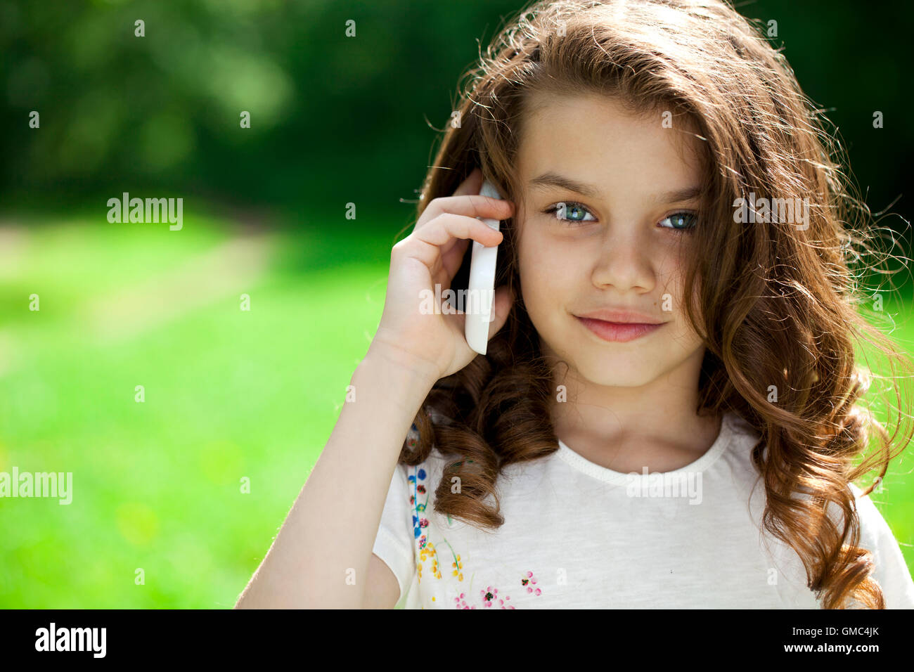 Beautiful little girl calling by mobile phone on the background of ...