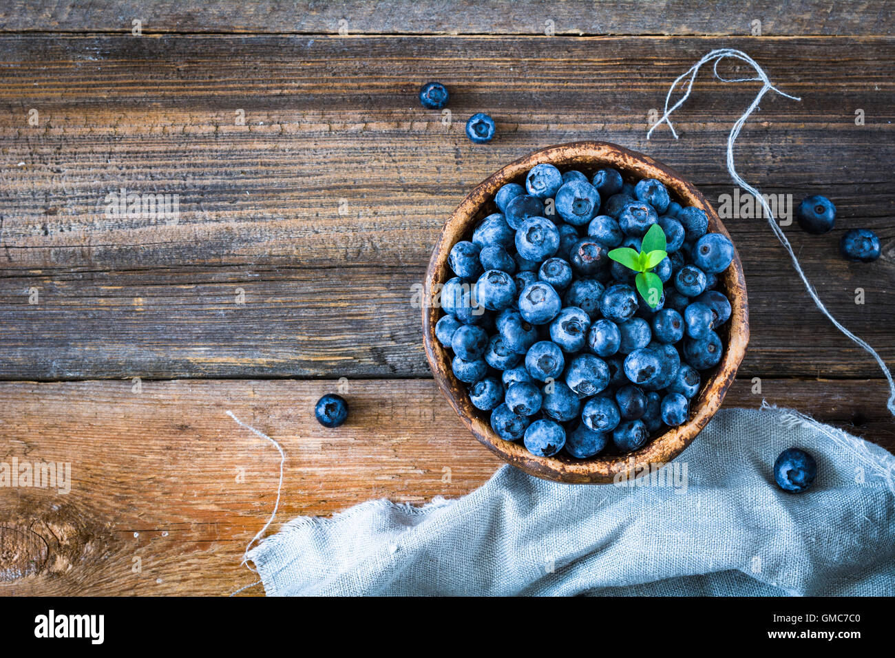 Freshly picked blueberries in a bowl on wooden background with copy ...