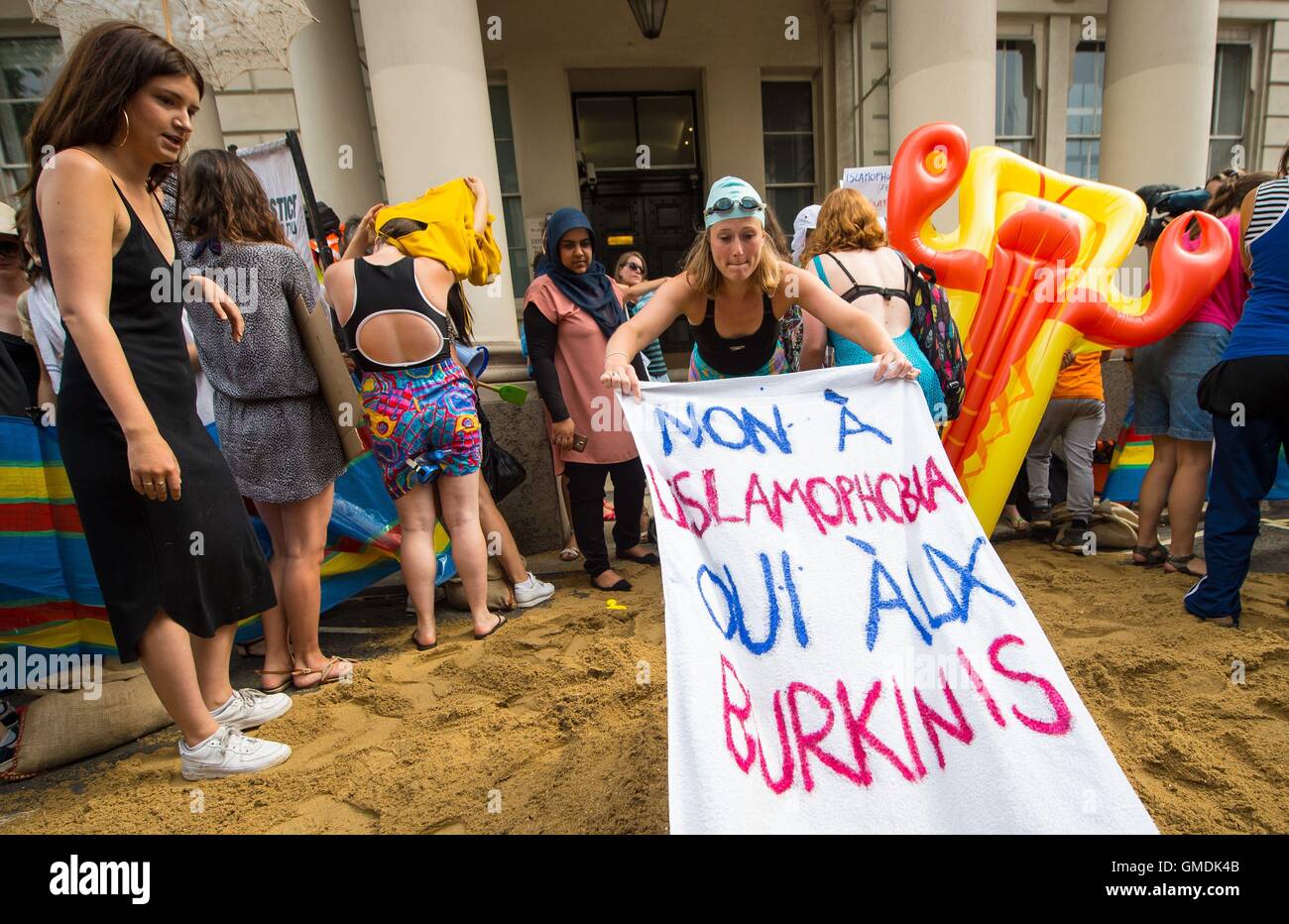 A woman lays out a towel as demonstrators stage a beach party outside ...