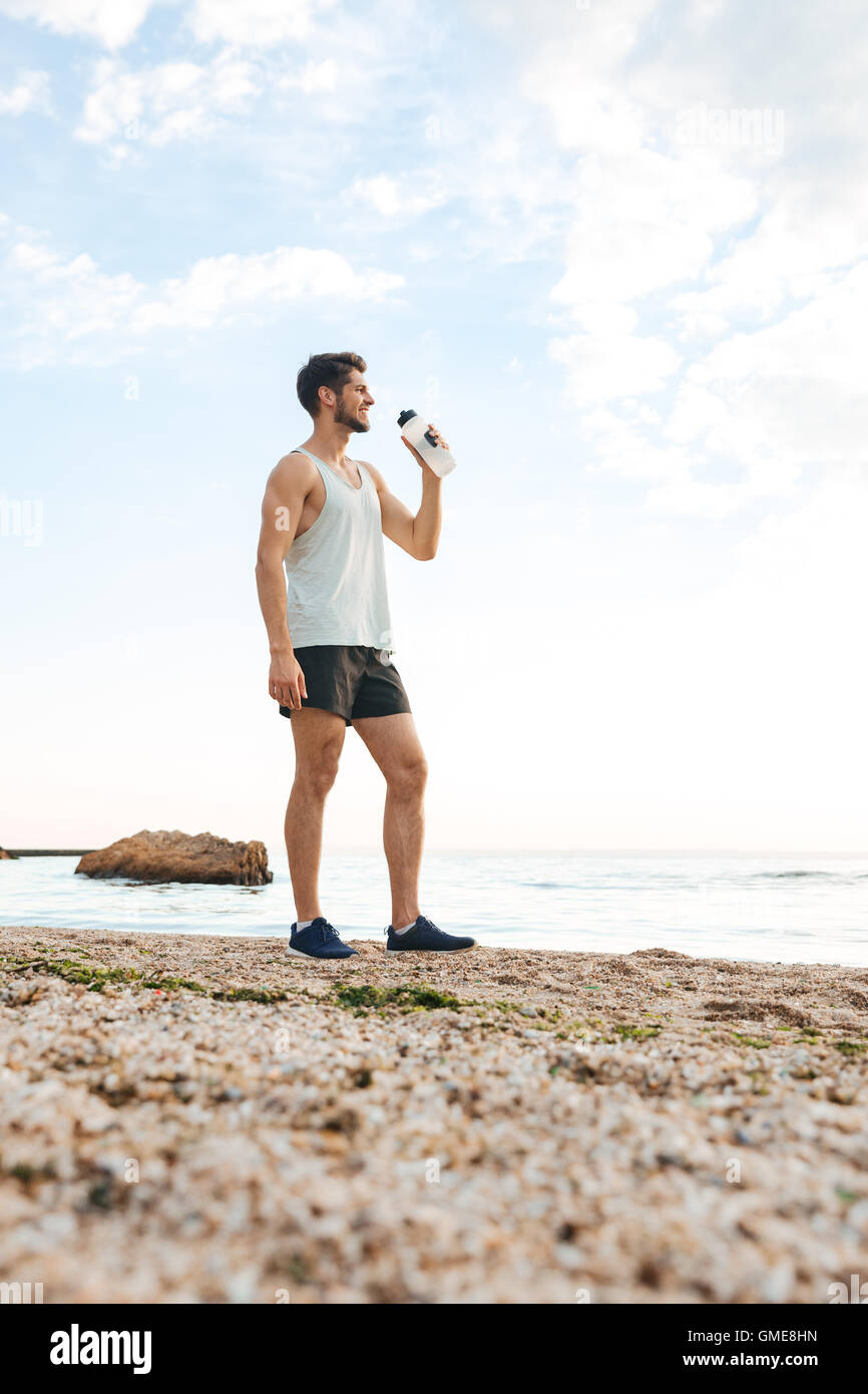 Young sporty man athlete resting after jogging at the beach and ...
