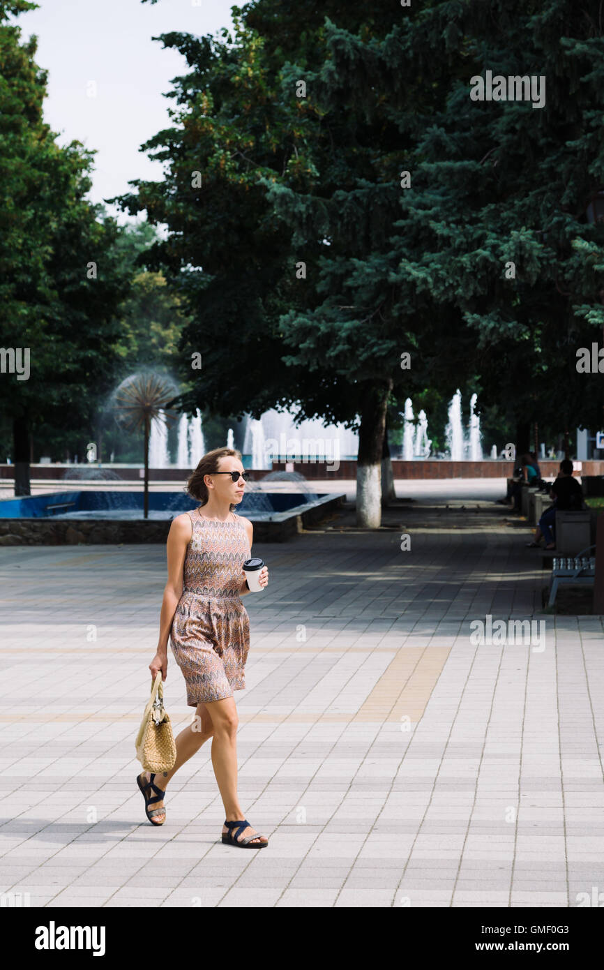 Young brunette woman with coffee cup walking in city Stock Photo - Alamy