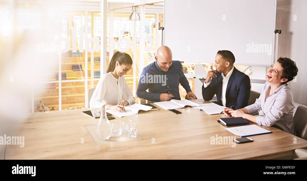 Four business people laughing during a professional board room meeting ...