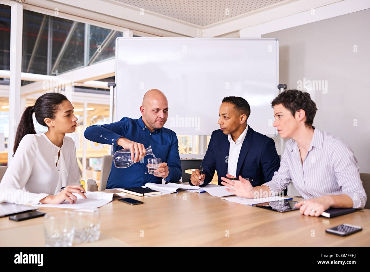 businessman pouring himself water during meeting with fellow colleagues ...