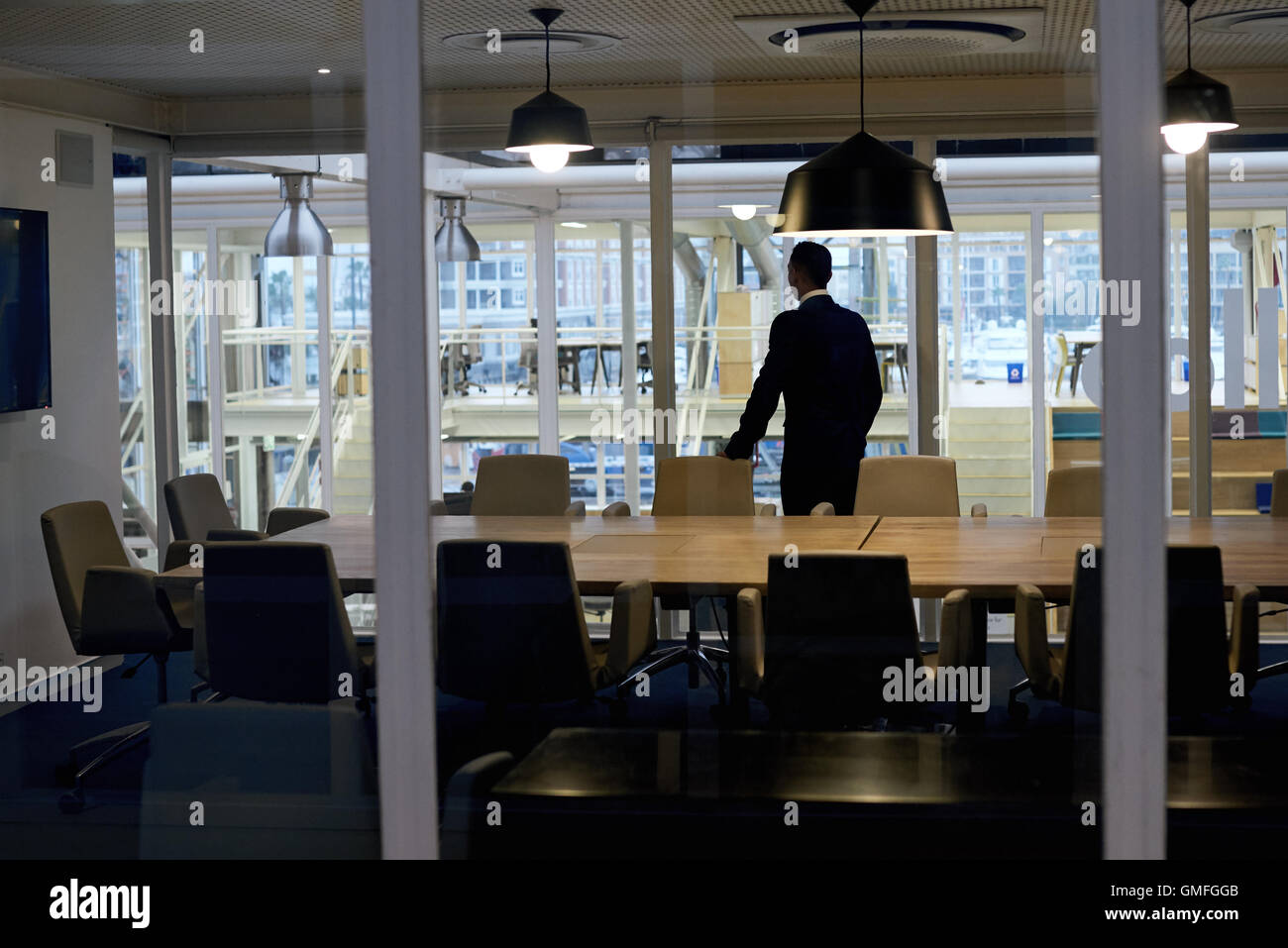 Aspirational businessman standing in empty conference room looking out ...