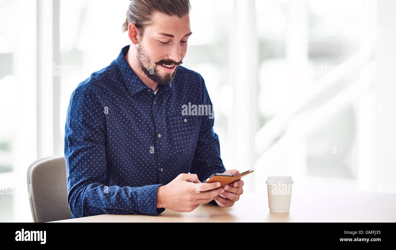Trendy man busy looking at his phone screen while texting Stock Photo ...