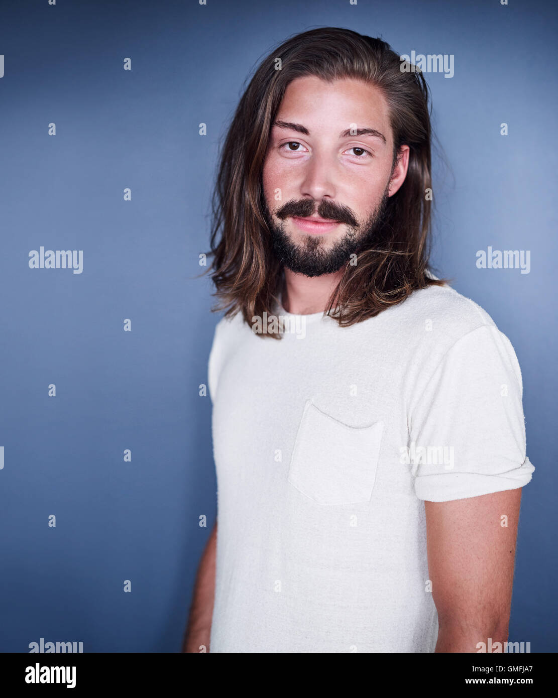 Handsome caucasian man with long brown hair against blue background ...