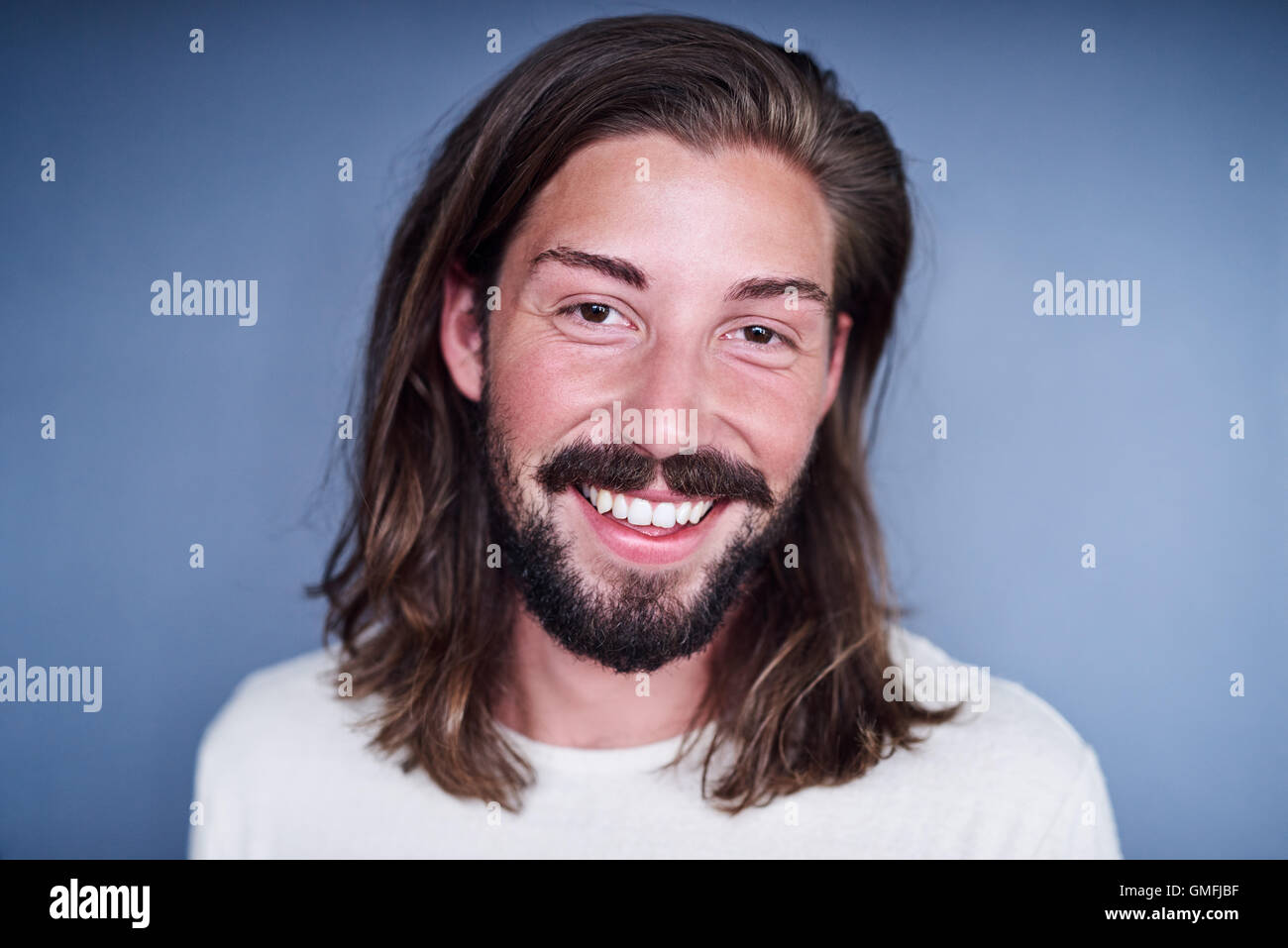 Handsome caucasian man with long brown hair against blue background ...