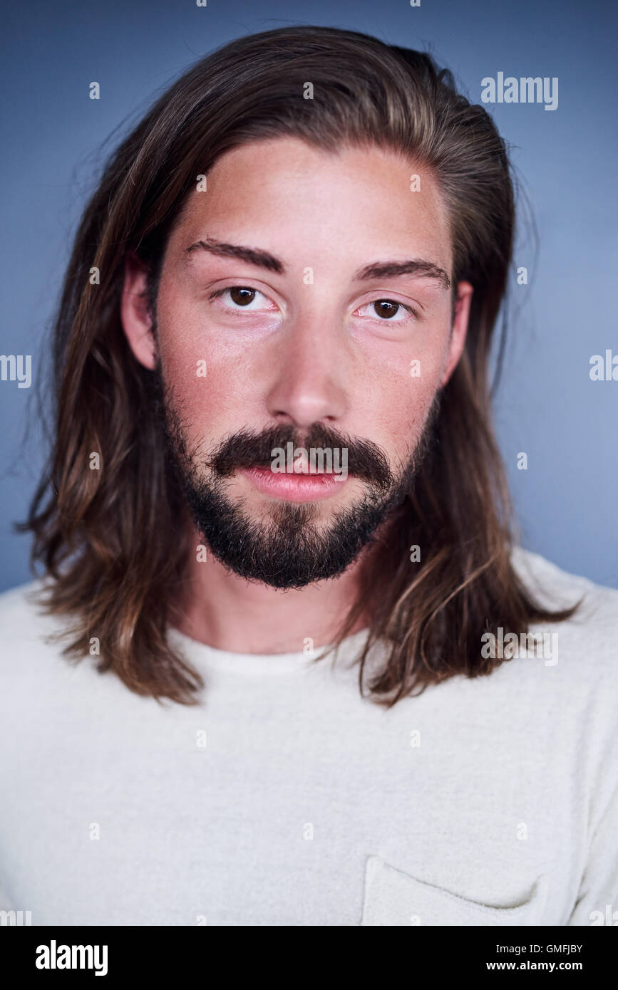 Handsome caucasian man with long brown hair against blue background ...