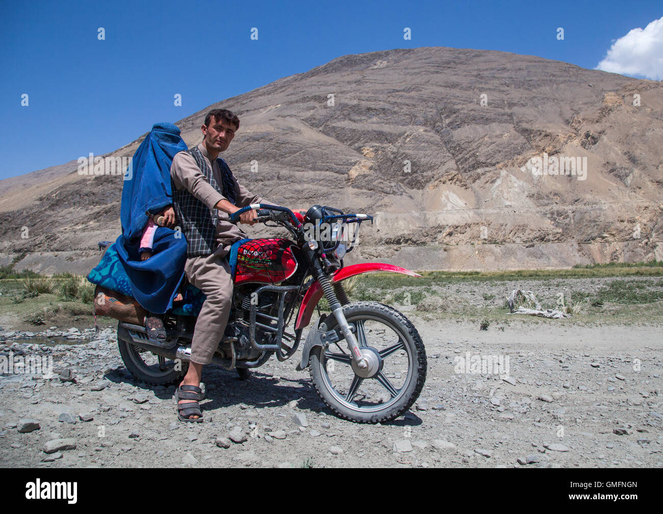 Afghan man riding a motorcycle with his wife wearing a burka ...