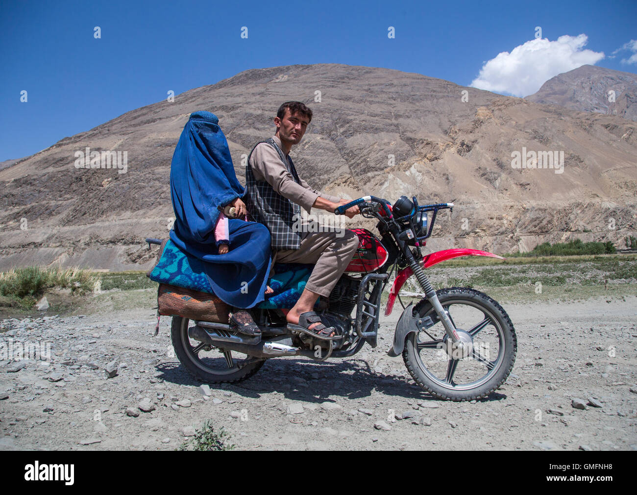 Afghan man riding a motorcycle with his wife wearing a burka ...