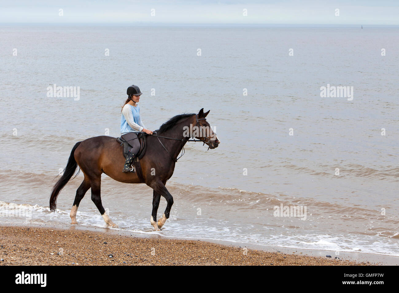 Horse riding along shoreline at the English seaside village of ...