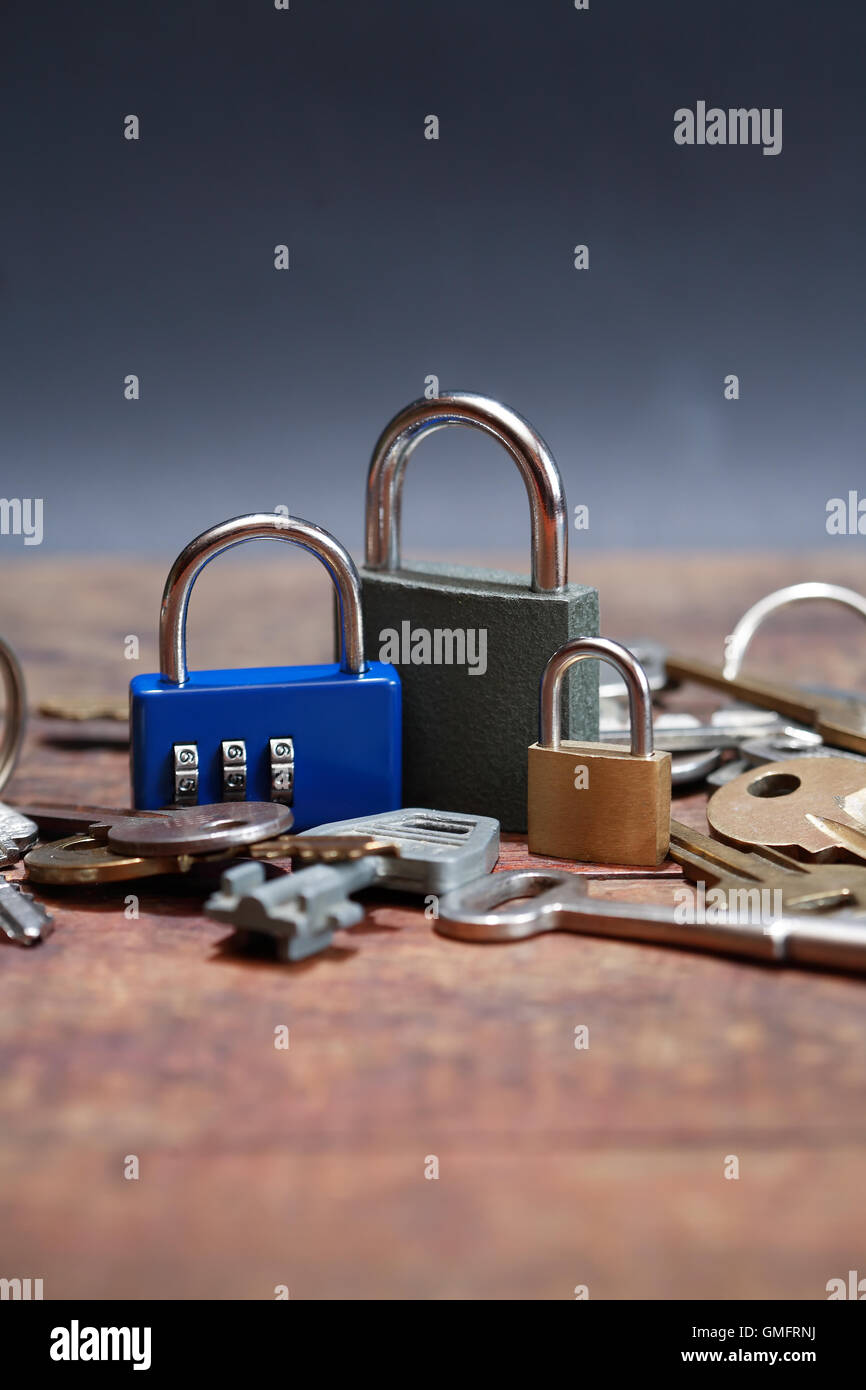 Three padlocks near keys on wooden board against dark background Stock ...