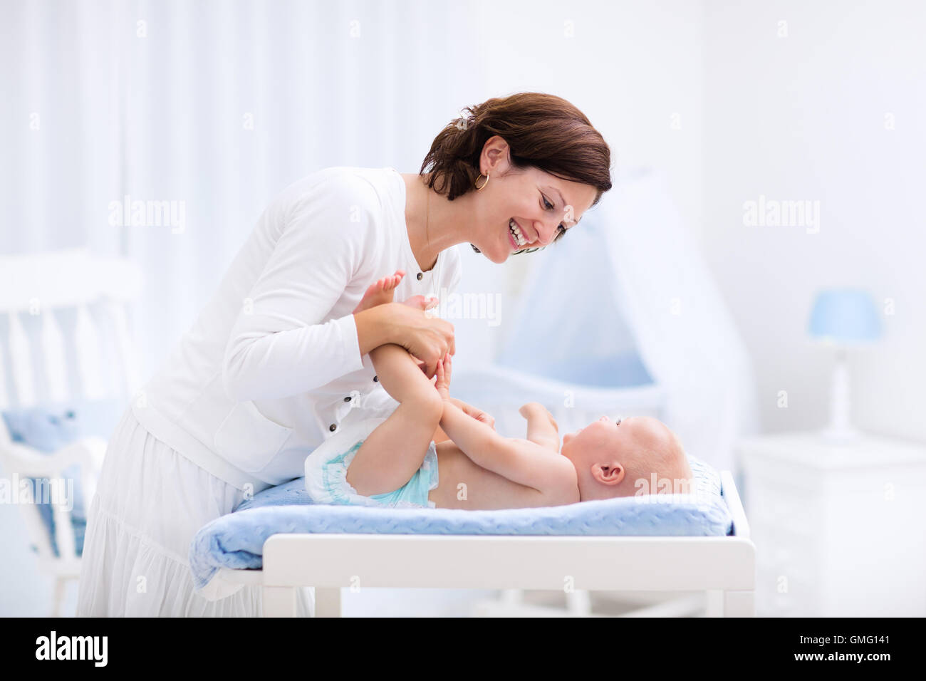 Young mother taking care of little boy in white sunny nursery with ...