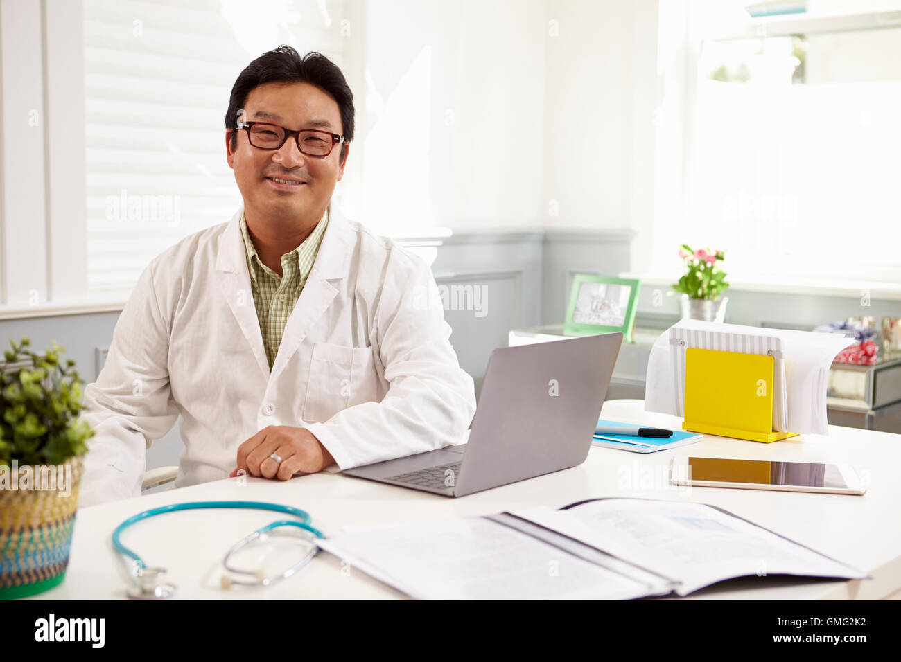 Male Doctor Sitting At Desk Working At Laptop In Office Stock Photo - Alamy