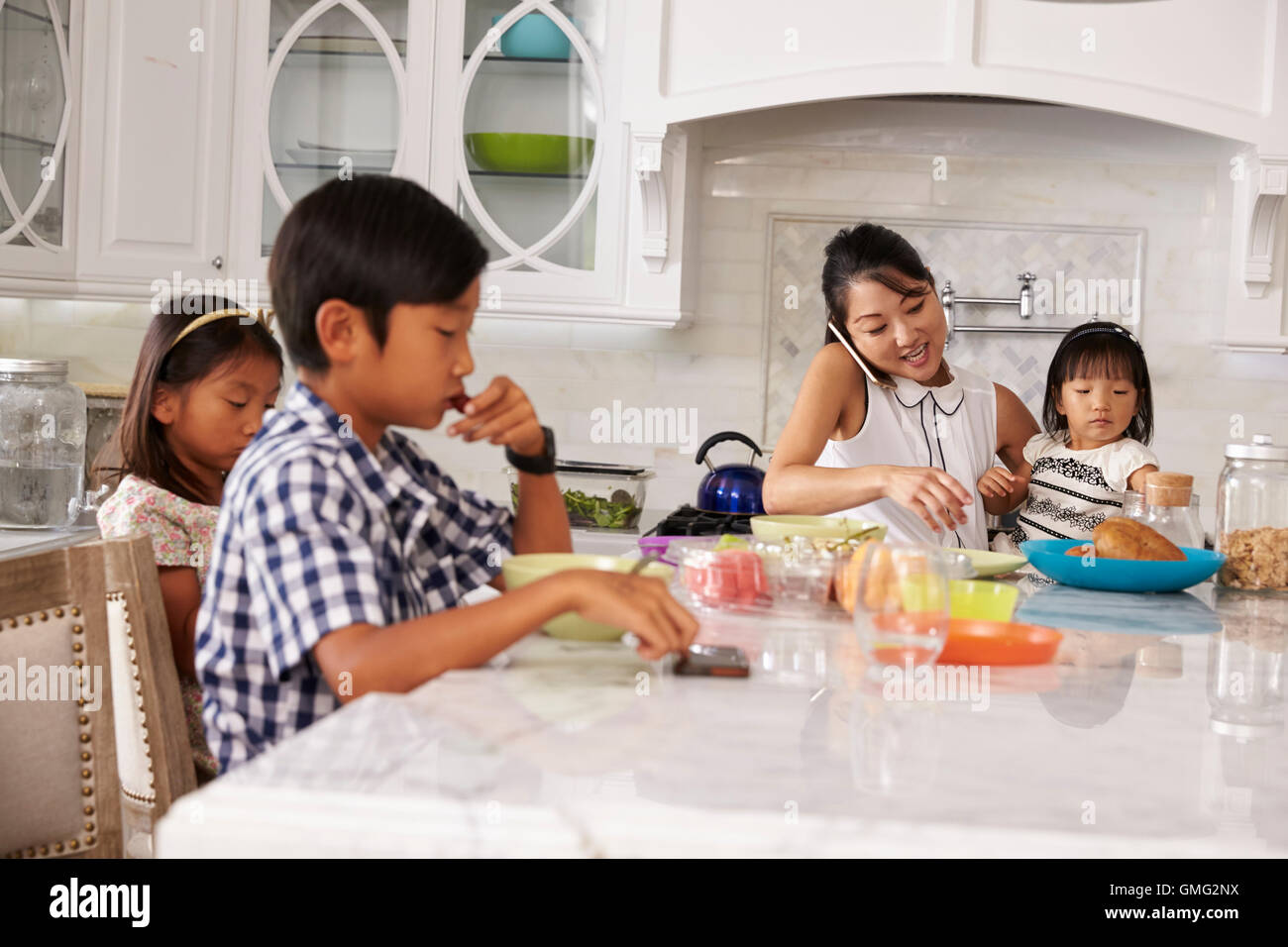 Busy Mother Organizing Children At Breakfast In Kitchen Stock Photo - Alamy