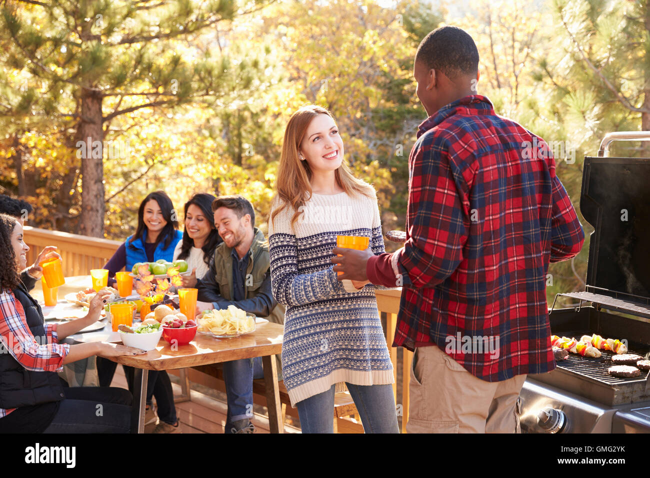 Group at a table behind two friends talking at a barbecue Stock Photo ...
