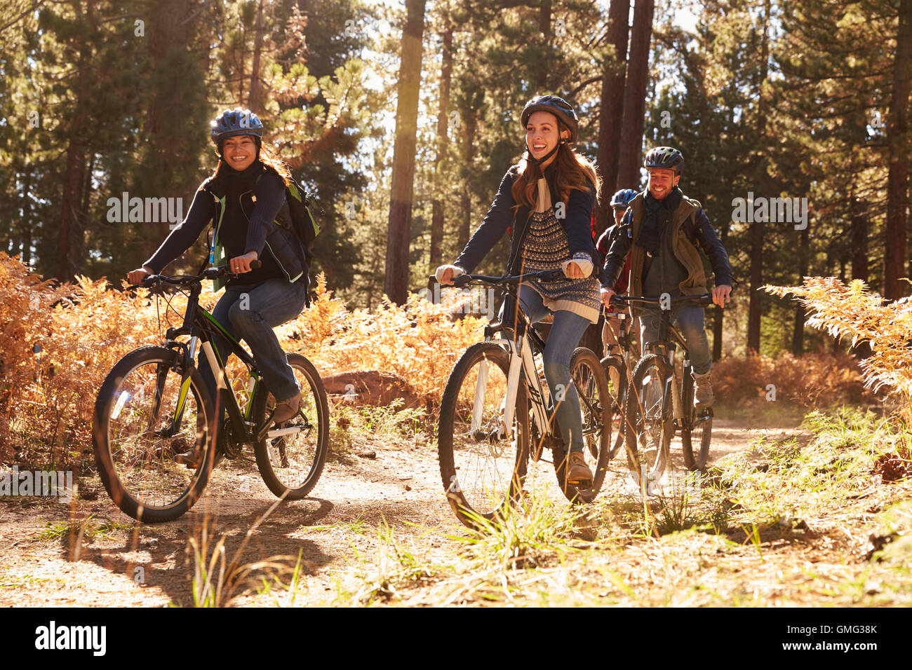 Group of smiling friends riding bikes in a forest, side view Stock ...