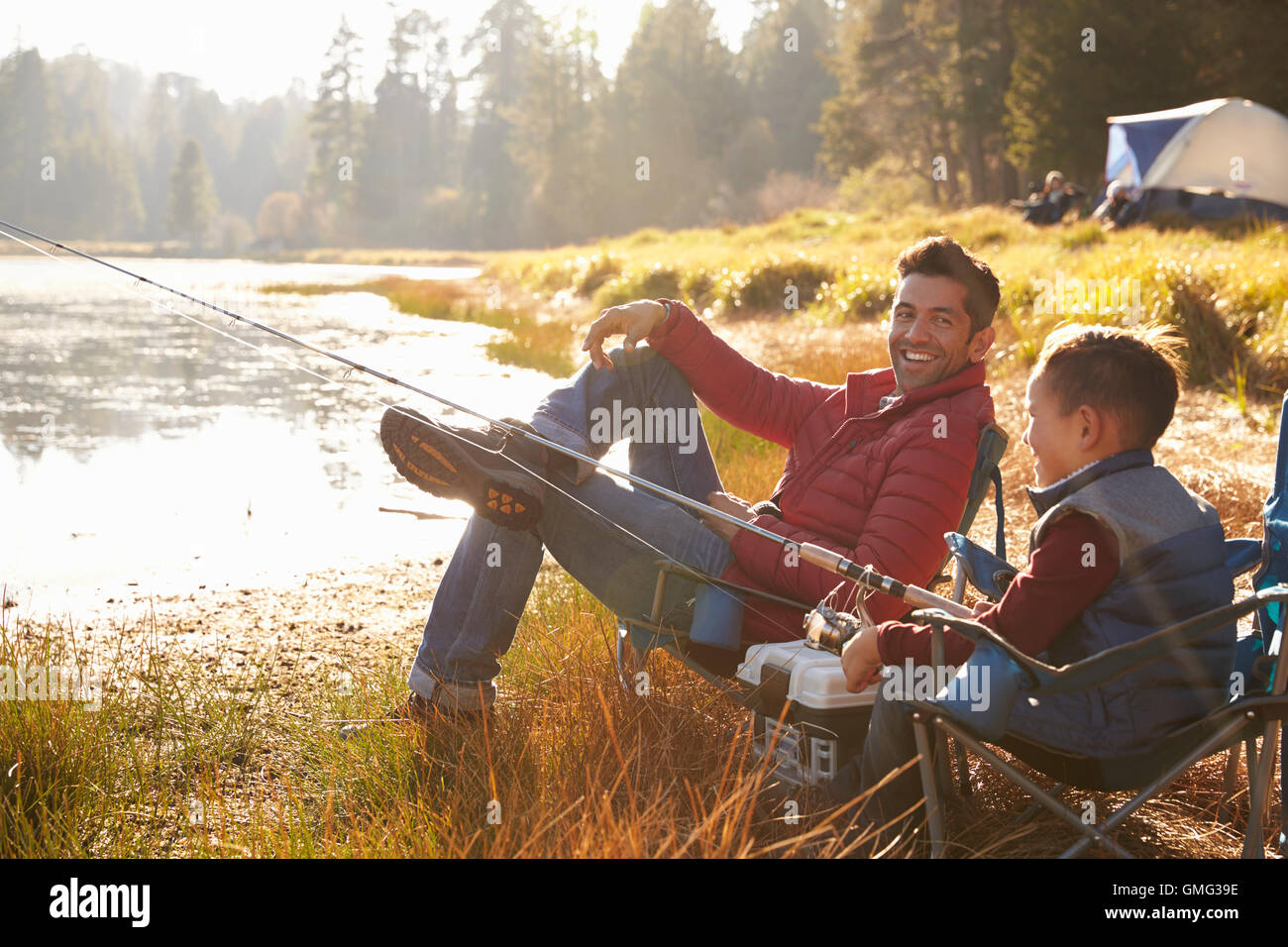 Father and son fishing by a lake, dad looks to camera Stock Photo - Alamy