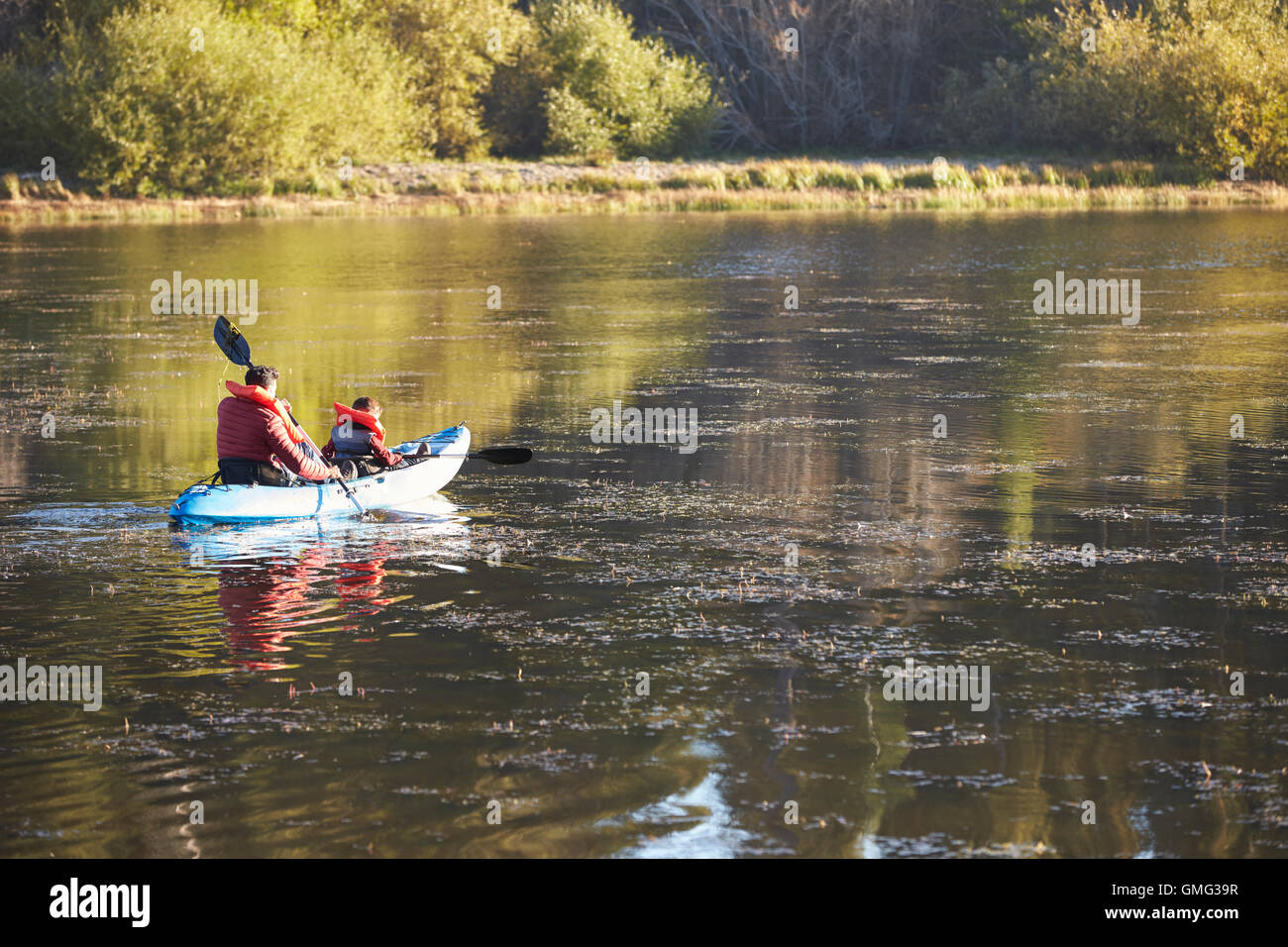 Father and son kayaking on a lake, back view, distant Stock Photo - Alamy