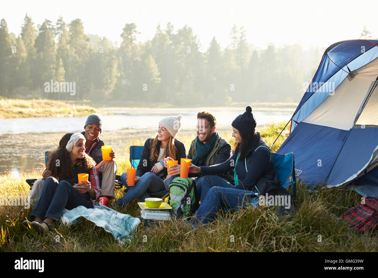Group of friends sitting outside their tent near a lake Stock Photo - Alamy