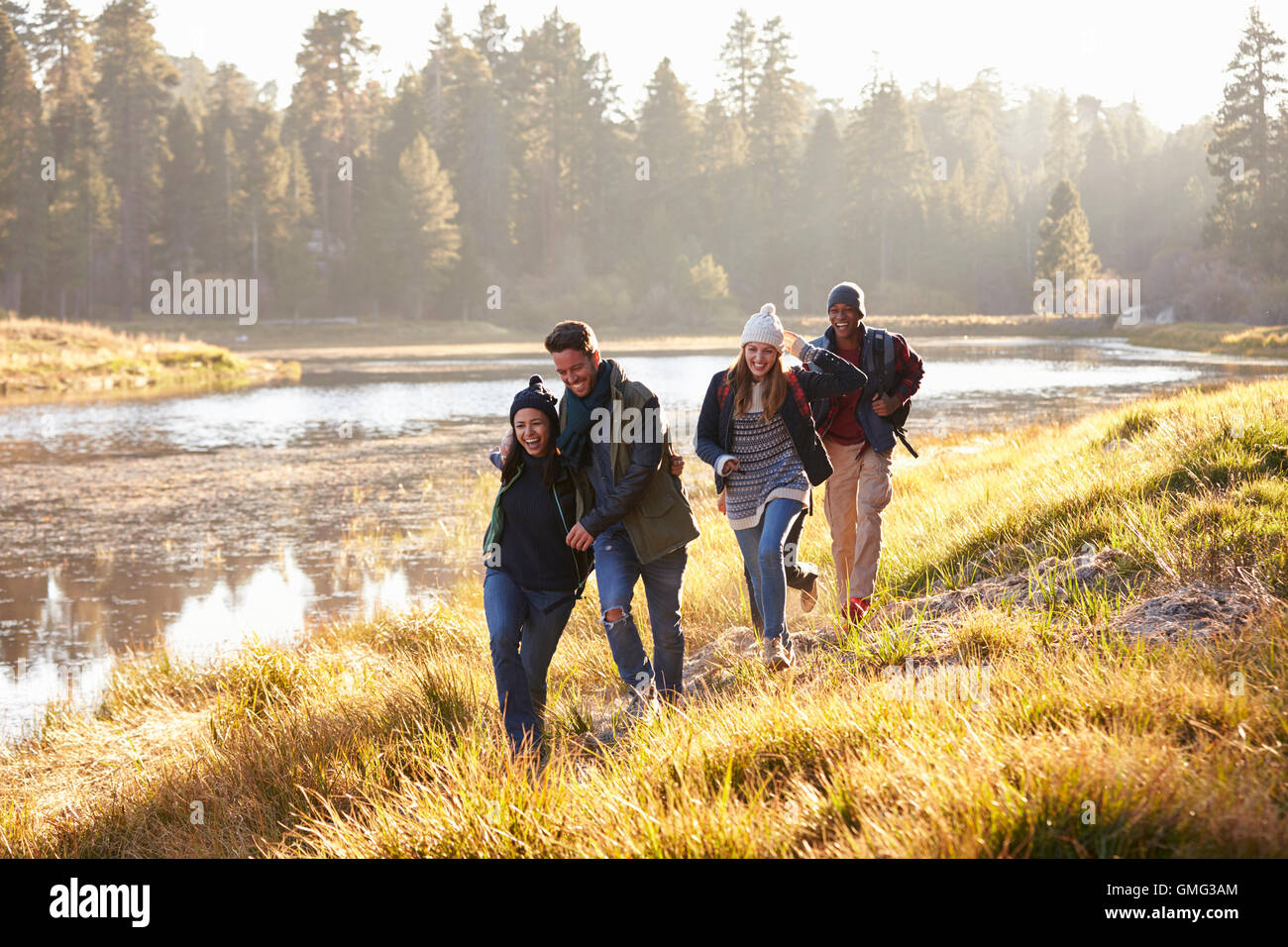 Four friends having fun walking beside a lake Stock Photo - Alamy