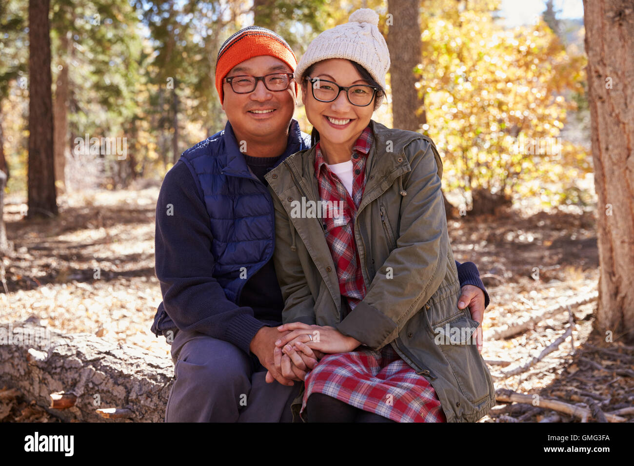 Happy Asian couple sitting in a forest looking to camera Stock Photo - Alamy