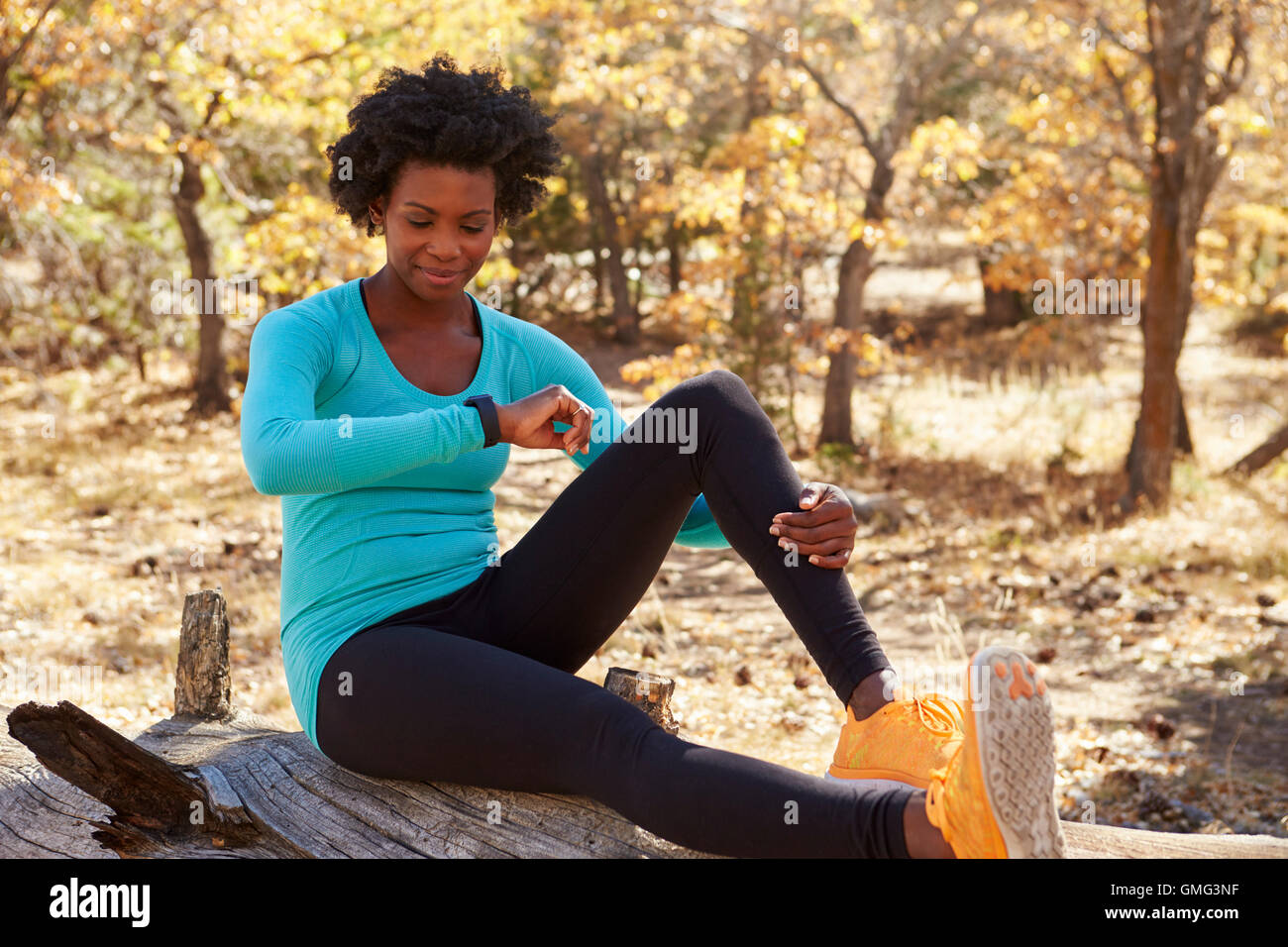 Black female runner sitting in a forest checking smartwatch Stock Photo ...