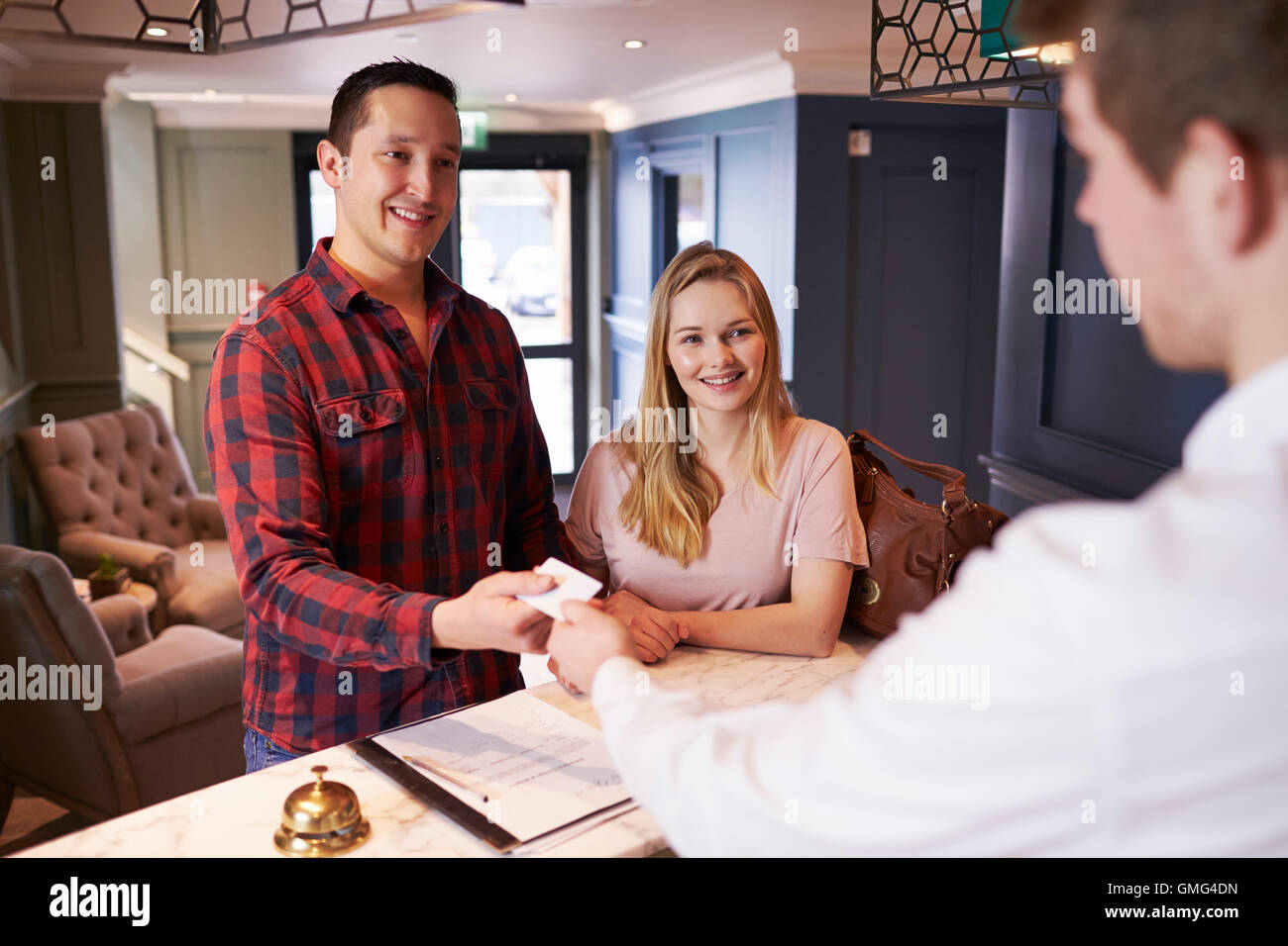 Couple Checking In At Hotel Reception Desk Stock Photo - Alamy
