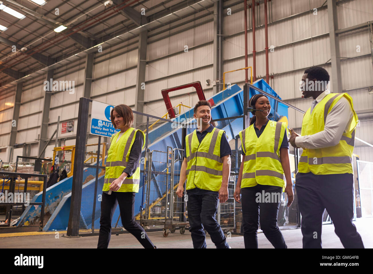 Four coworkers talk as they walk in an industrial interior Stock Photo ...