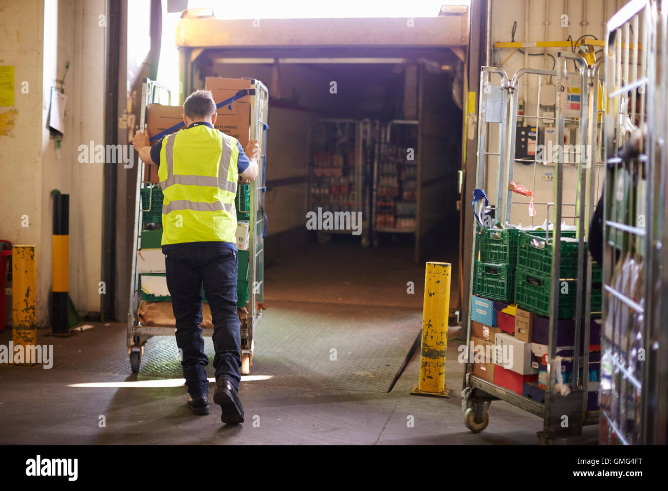 Man pushing roll cage into a truck at a warehouse, back view Stock ...