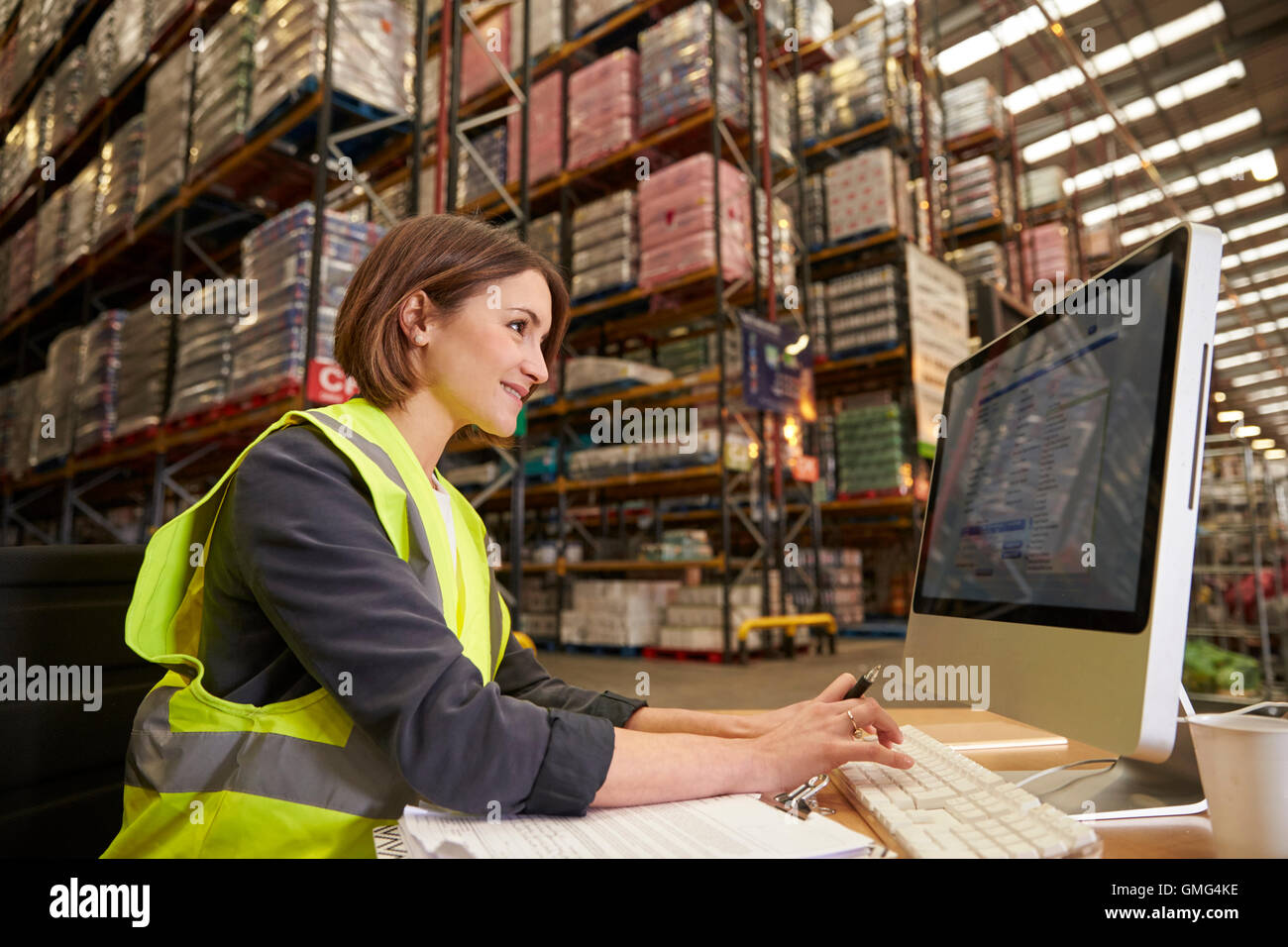 Woman working at computer in on-site office of a warehouse Stock Photo ...