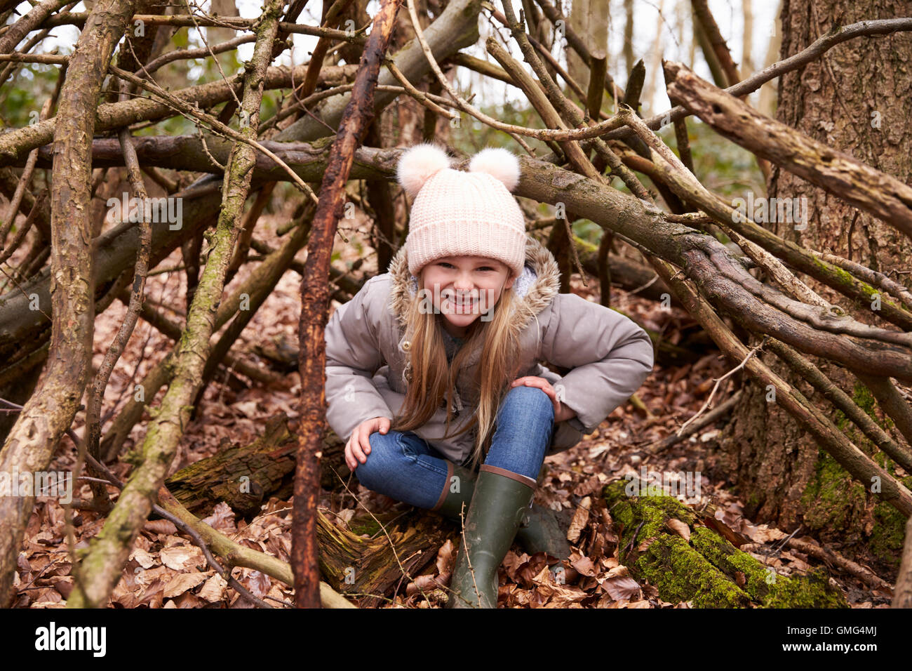 Young girl sits under shelter of tree branches, full length Stock Photo ...