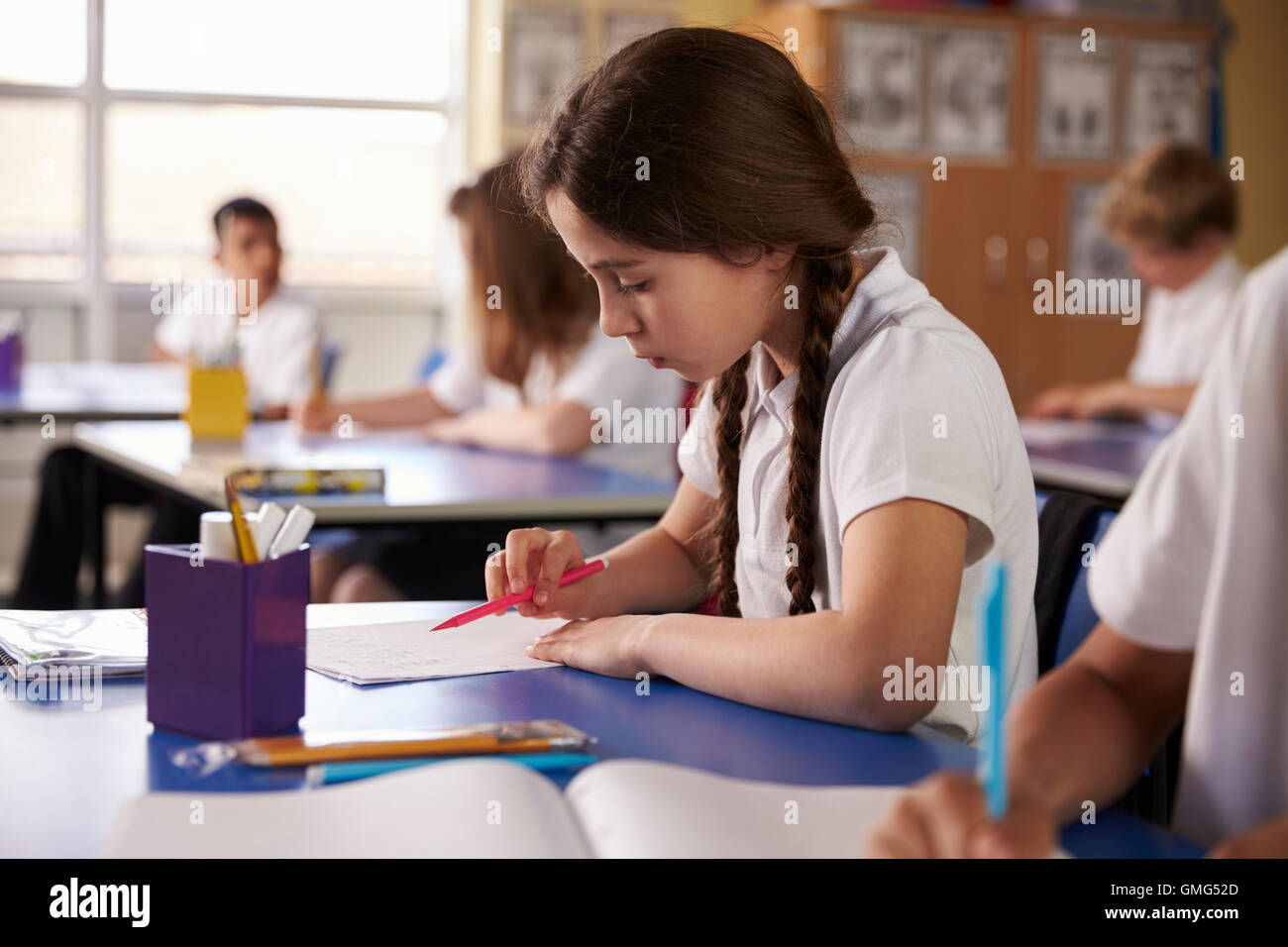 Primary school girl working at her desk in class Stock Photo - Alamy